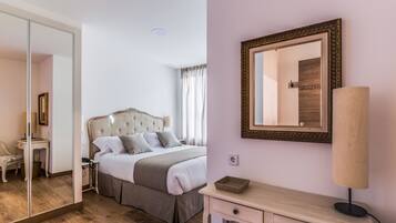 Um quarto com cama, mesa de cabeceira, abajur e espelho na parede.