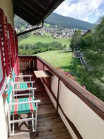 Uma varanda com piso de madeira, uma mesa e cadeiras.