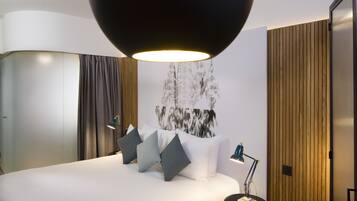 Quarto de hotel moderno com uma cama grande, uma escrivaninha e um candeeiro de parede imponente.