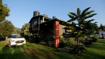 Uma casa com garagem, um pilar de tijolos e um gramado com diversas plantas.