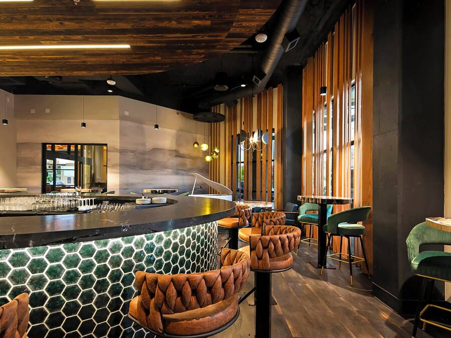 Uma área de bar com balcão, banquetes e vista para o exterior.