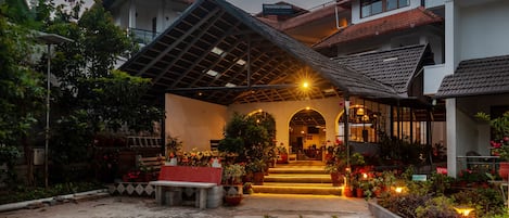 Um edifício com entrada coberta, área de estar ao ar livre e vasos de plantas.