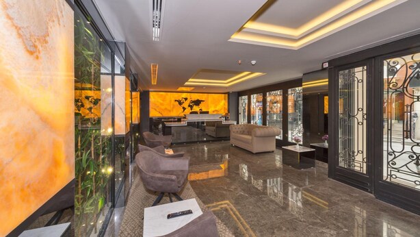 Um hall moderno com uma receção de mármore, área de estar e painéis de vidro decorativos.