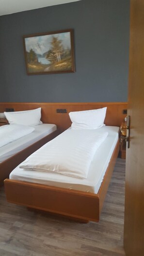 Quarto de hotel com duas camas de solteiro, cabeceiras de madeira e um quadro na parede.