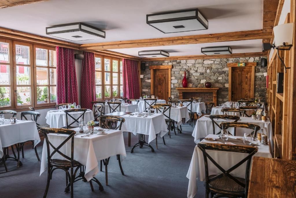 Um restaurante com várias mesas e cadeiras, uma parede de pedra e uma lareira.