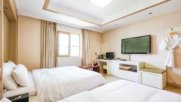 Quarto de hotel com duas camas, uma secretária com televisão e um roupão pendurado na parede.