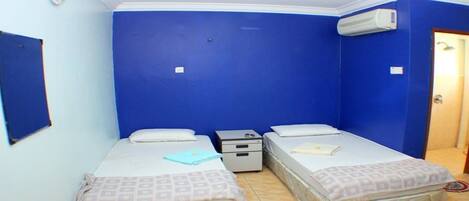 Quarto com duas camas, uma mesinha e ar-condicionado fixado na parede.