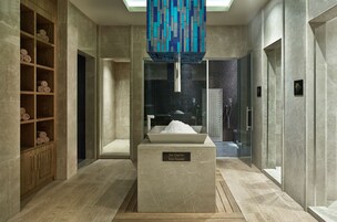 Um banheiro moderno com piso de mármore, uma prateleira de madeira com toalhas, um box de vidro e uma etiqueta com a inscrição "Kar Cezmesi Snow Fountain".