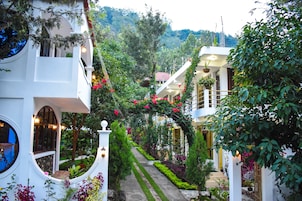 Um edifício branco com um caminho de jardim que leva a uma varanda.