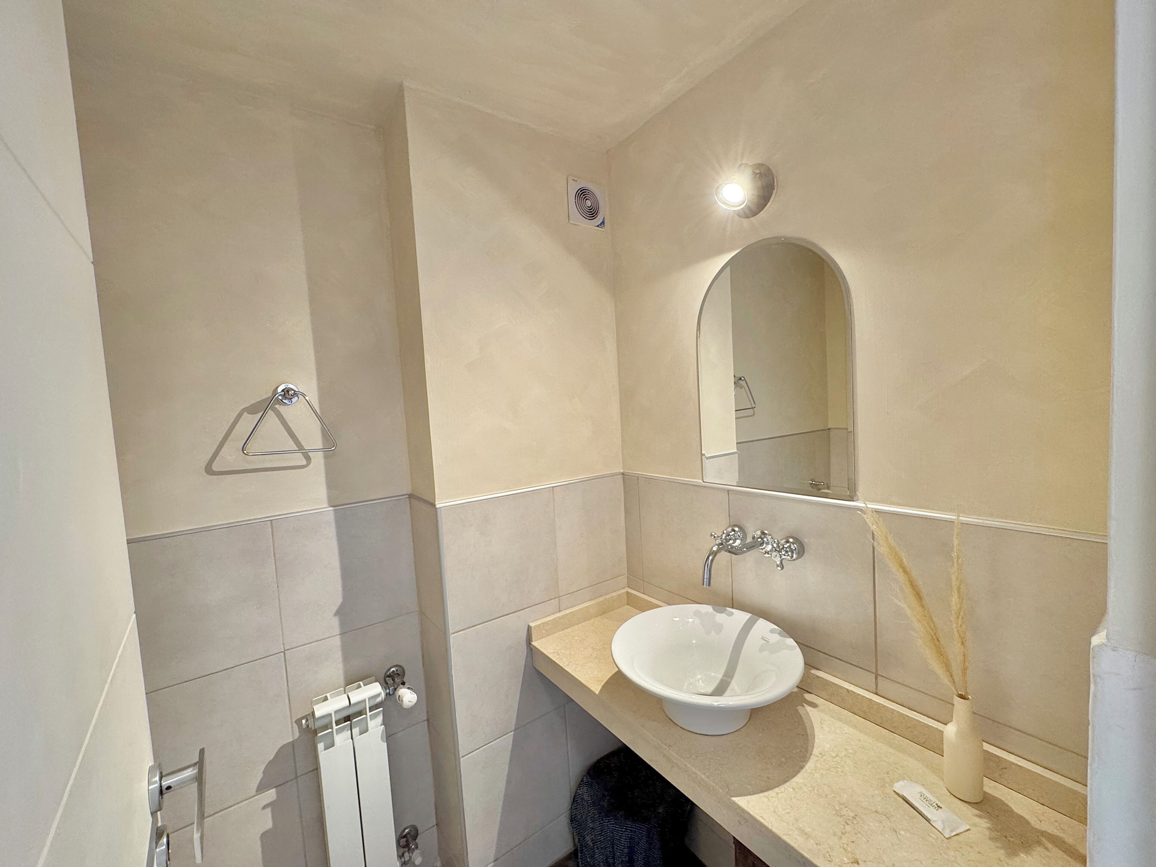 Casa de banho com lavatório branco, espelho e porta-toalhas.