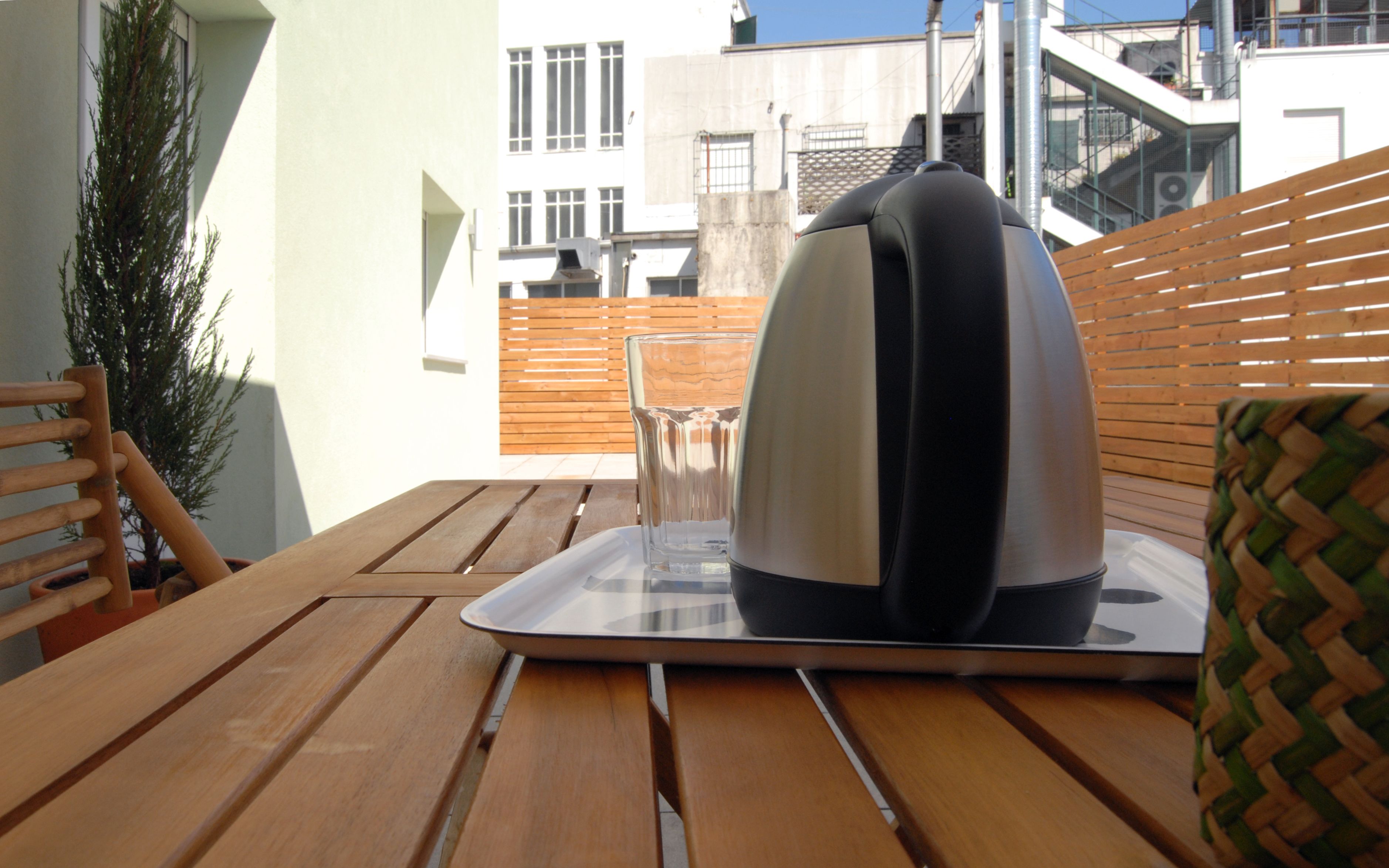 Mesa com chaleira, copo e almofada trançada.