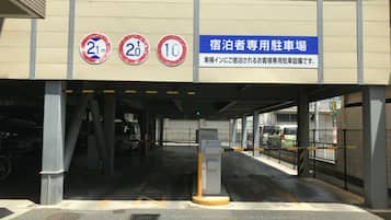 Entrada de garagem com placas de restrição de altura e sinalização indicando área de estacionamento para hóspedes do hotel.