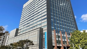 Um edifício alto e moderno, com uma fachada de janelas em grade e entrada destacada.