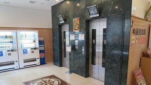 Um saguão com máquinas de venda automática, uma parede de mármore e um elevador.