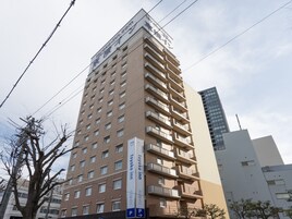 Um hotel alto com vários andares, uma placa indicando que é um hotel e um aviso de estacionamento abaixo.
