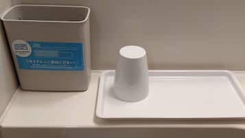 Uma pia de banheiro com uma lixeira e um porta-copos.
