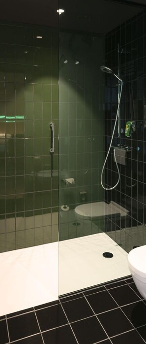 Um banheiro moderno com chuveiro em box de vidro, pia branca e piso de azulejos pretos.