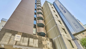 Um edifício alto de hotel com design moderno, apresentando uma placa grande com a inscrição 'toyoko inn' na lateral.
