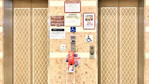 Interior de elevador com painel de controle, botão de emergência e dispensador de álcool em gel.