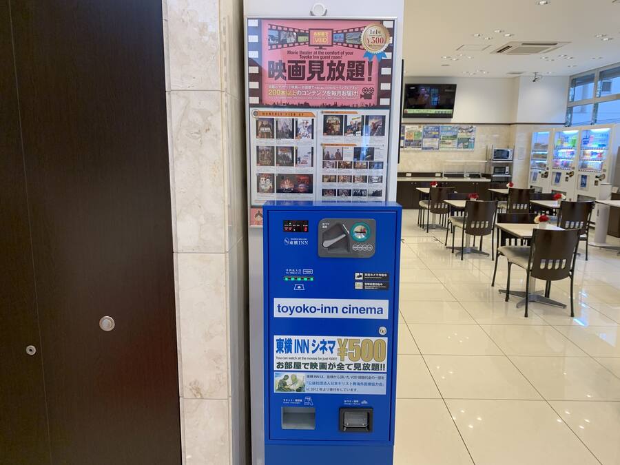 Máquina de venda de bilhetes de cinema com um aviso a anunciar um passe mensal por 500 ienes.