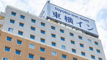 Um edifício de vários andares com uma placa indicando 'toyoko-inn.com' e caracteres japoneses.