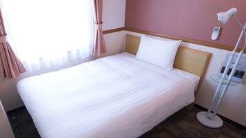 Quarto de hotel com uma cama de solteiro, uma mesa de cabeceira com abajur e um painel de controle fixado na parede.