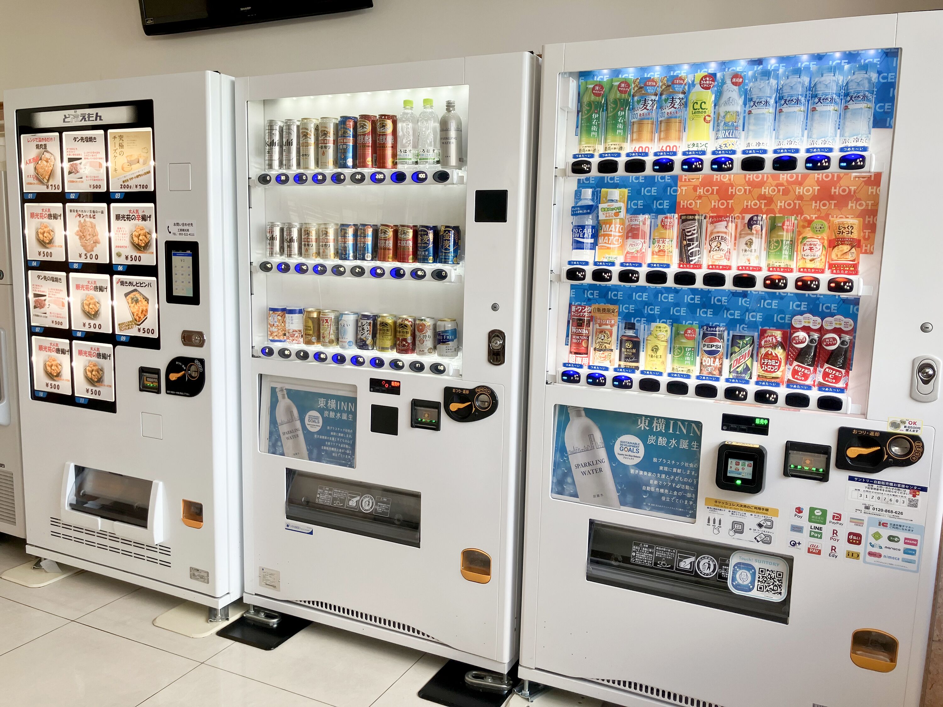 Três máquinas de venda automática com diversas bebidas e lanches.