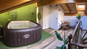 Um quarto aconchegante com hidromassagem, uma escada de madeira e vista para o exterior.