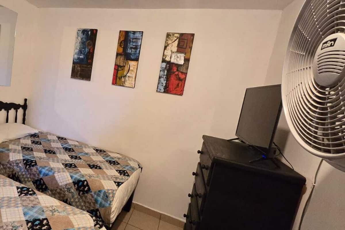 Quarto com duas camas, penteadeira, televisão e obras de arte na parede.