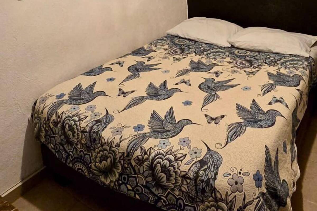 Quarto com cama, pintura, televisão e uma cadeira.