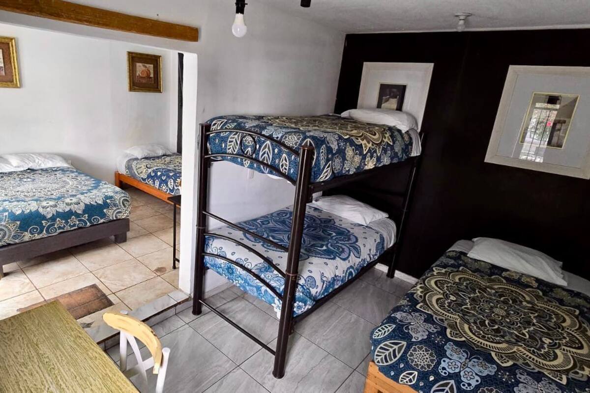 Um dormitório com beliches, uma mesa pequena e cadeiras.