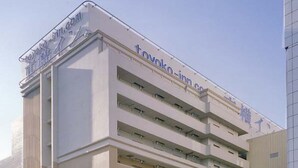 Um edifício com vários andares, fachada plana e uma placa com a inscrição "Tohoku Inn Co."