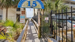 Entrada fechada para o acesso público à Praia do Condado de Bay, com aviso de proibição de animais de estimação, recipientes de vidro ou veículos na praia.