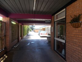Uma área de recepção com um carro estacionado na frente, um muro de tijolos e uma placa indicando recepção.