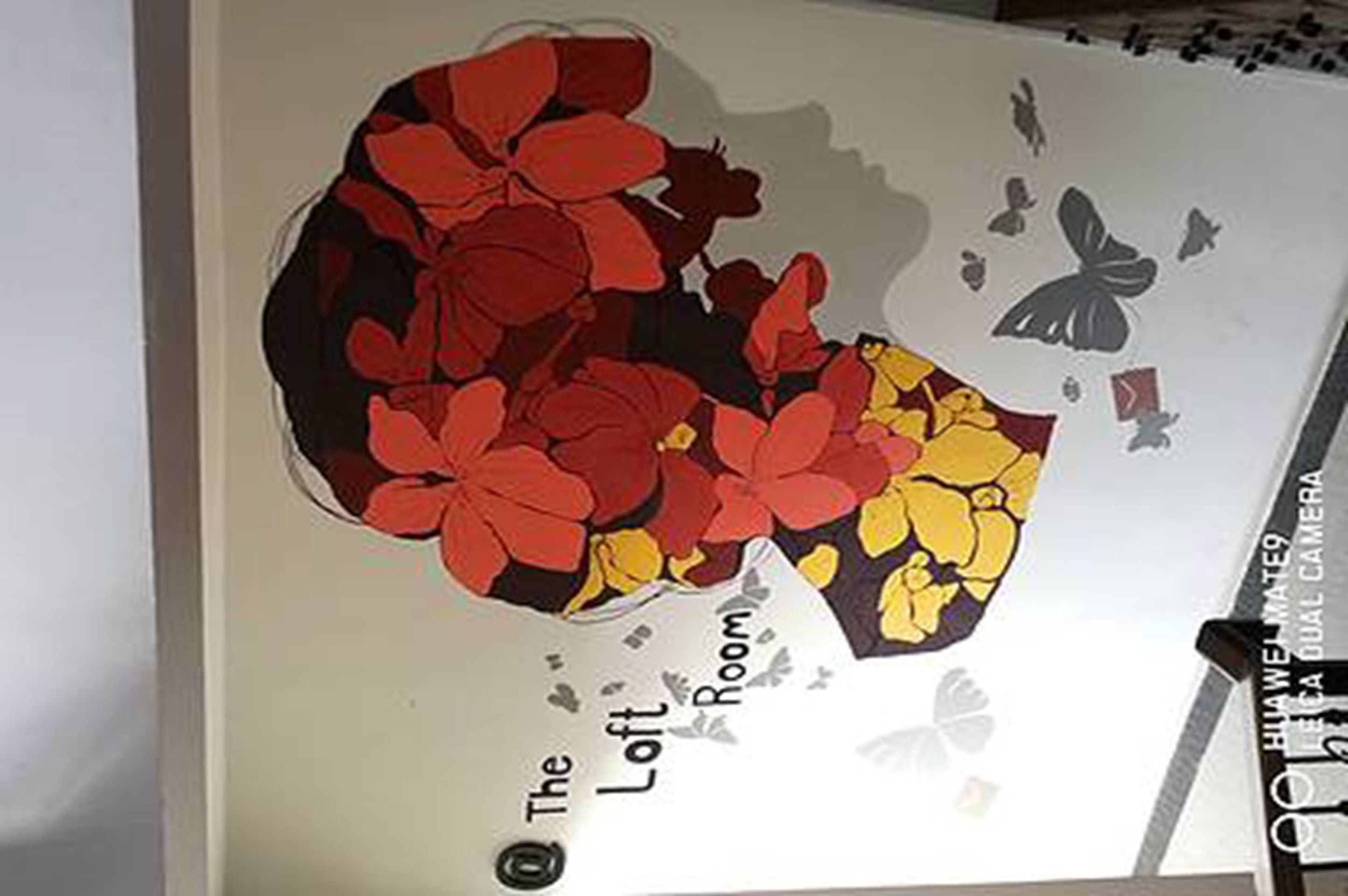Quarto com uma obra de arte floral na parede, uma cama e uma mesa de cabeceira.