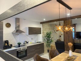 Uma cozinha moderna com parede de pedra, armários de madeira e área de jantar com mesa e cadeiras.