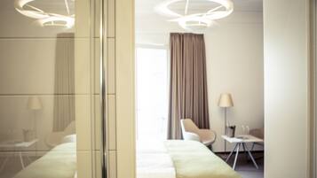 Quarto de hotel com cama, escrivaninha, cadeira e abajur.