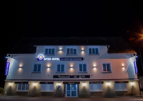A multi-story building with illuminated signs for "INTER-HOTEL" and "Le relais des Carnutes."