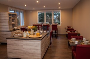 Uma sala de jantar espaçosa com uma ilha central, cadeiras estofadas em vermelho e diversos jogos de mesa.