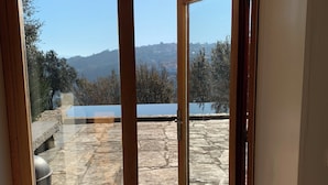 Quarto com pátio de pedra, vista para um lago e céu claro.