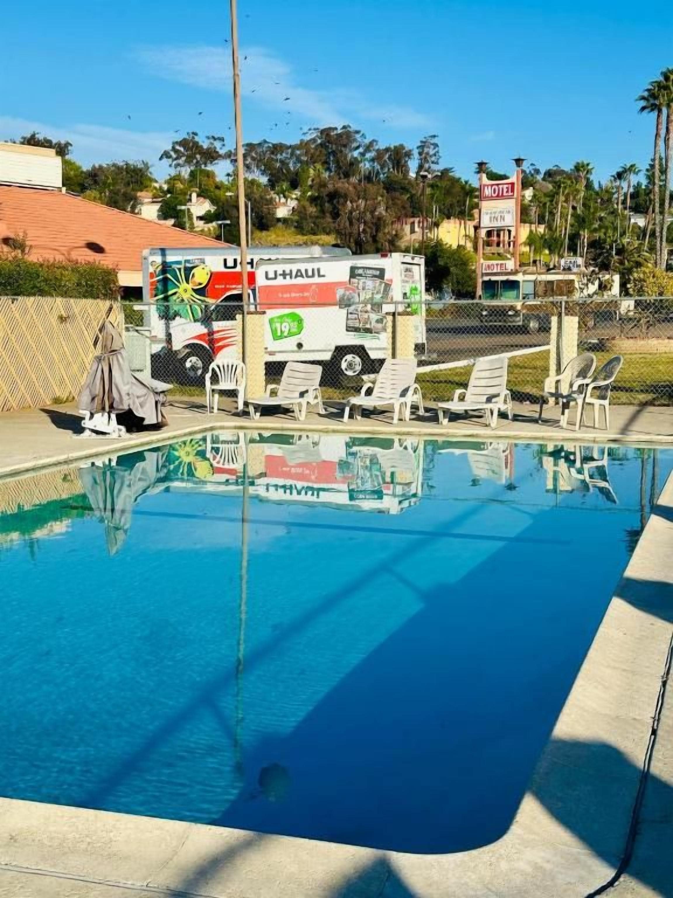Piscina com cadeiras de sol e uma caminhonete U-Haul estacionada perto.