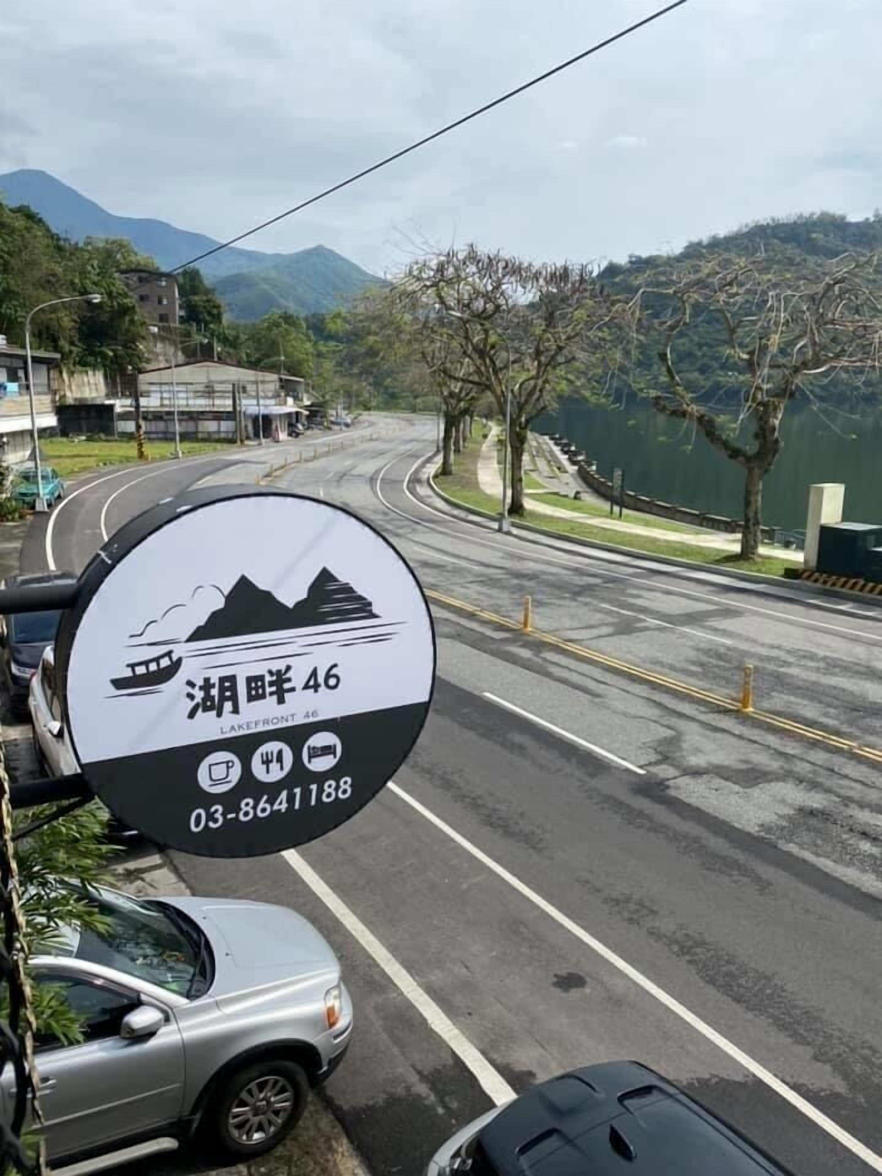 Um sinal redondo com ícone de montanha e lago, texto em língua estrangeira e um número de telefone.