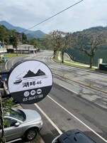 Um sinal redondo com ícone de montanha e lago, texto em língua estrangeira e um número de telefone.