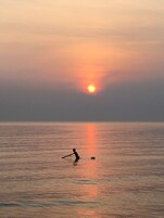 Uma pessoa pesca em águas calmas durante o pôr do sol.