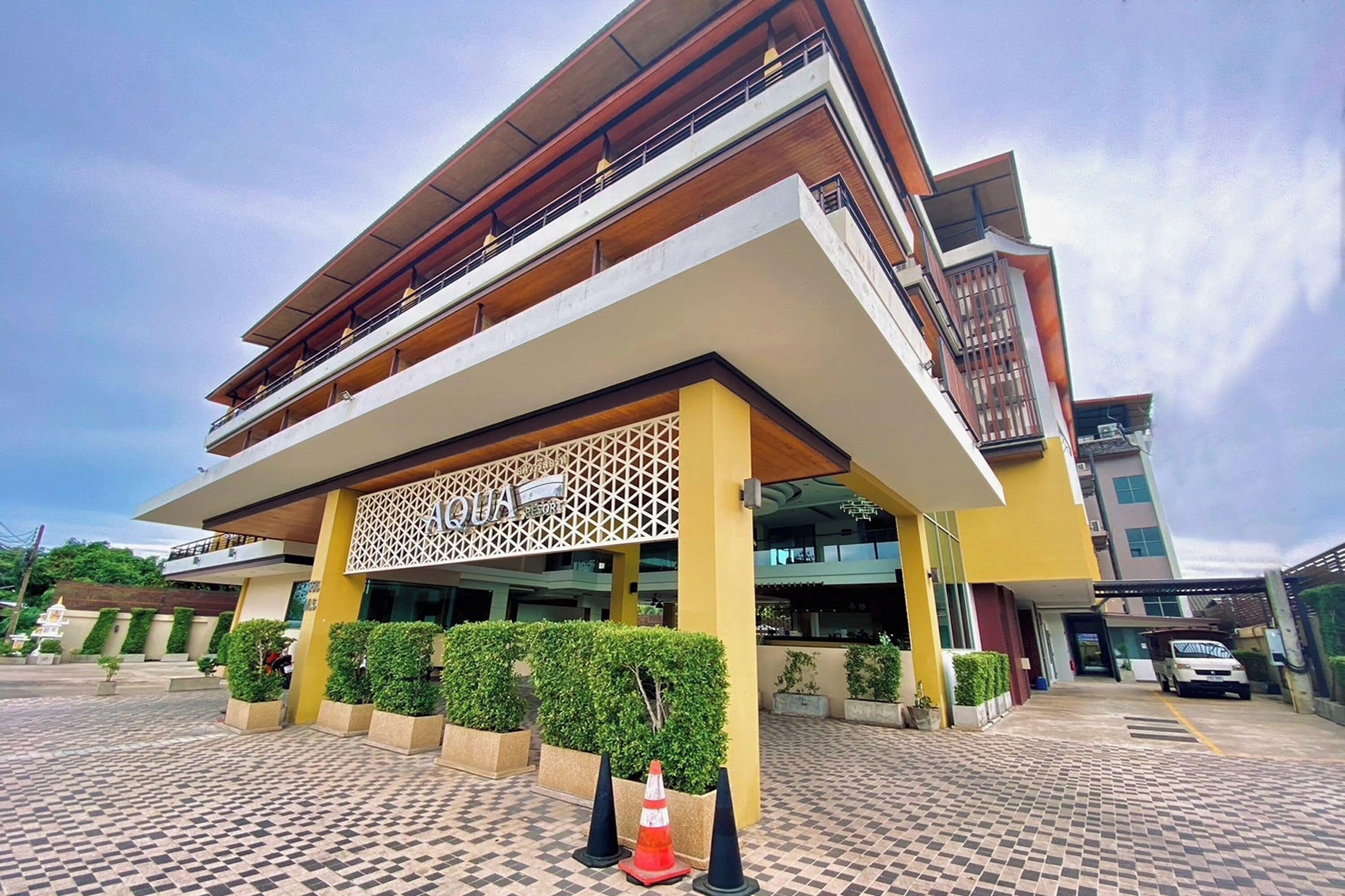 Um hotel moderno com entrada imponente, área externa coberta e vasos de plantas bem organizados.