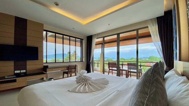 Quarto de hotel com uma cama grande, televisão de tela plana, escrivaninha e vista para o exterior.