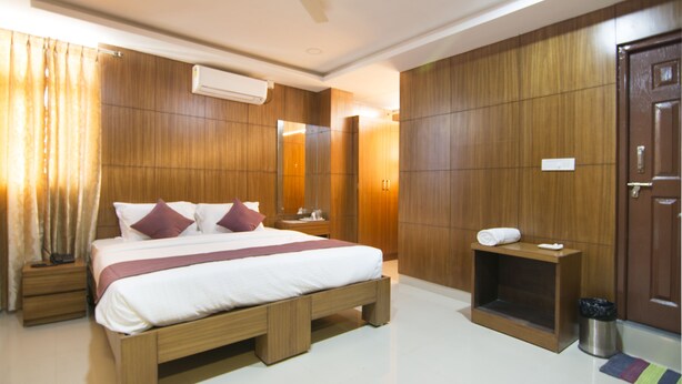 Quarto moderno com cama de madeira, mesa de cabeceira, pequeno armário de madeira e uma porta.