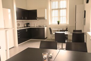 Cozinha moderna com armários pretos, sala de jantar com mesa e cadeiras, e uma janela com grades.