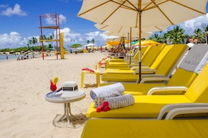 Na praia, espreguiçadeiras, guarda-sóis de praia, toalhas de praia