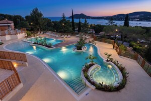 Uma área de piscina com espreguiçadeiras, uma banheira de hidromassagem e vista para o mar.